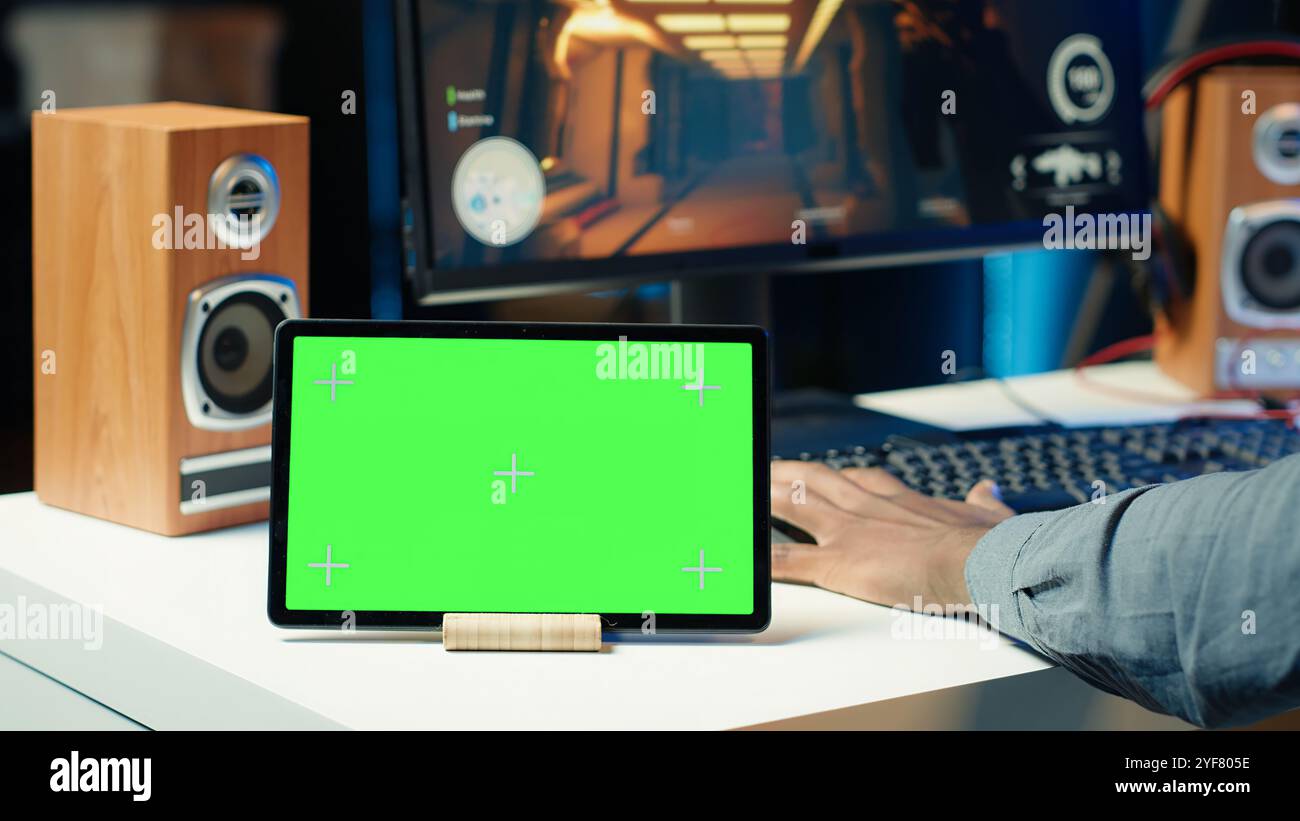 Chroma key tablet on desk next to man playing SF multiplayer videogame ...