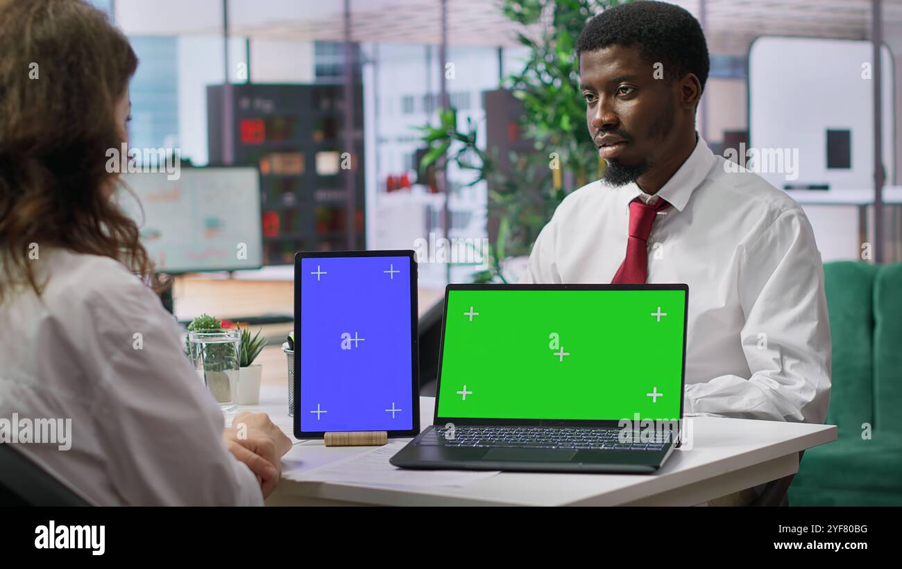 HR staff discussing with applicant next to mockup chroma key screens at ...