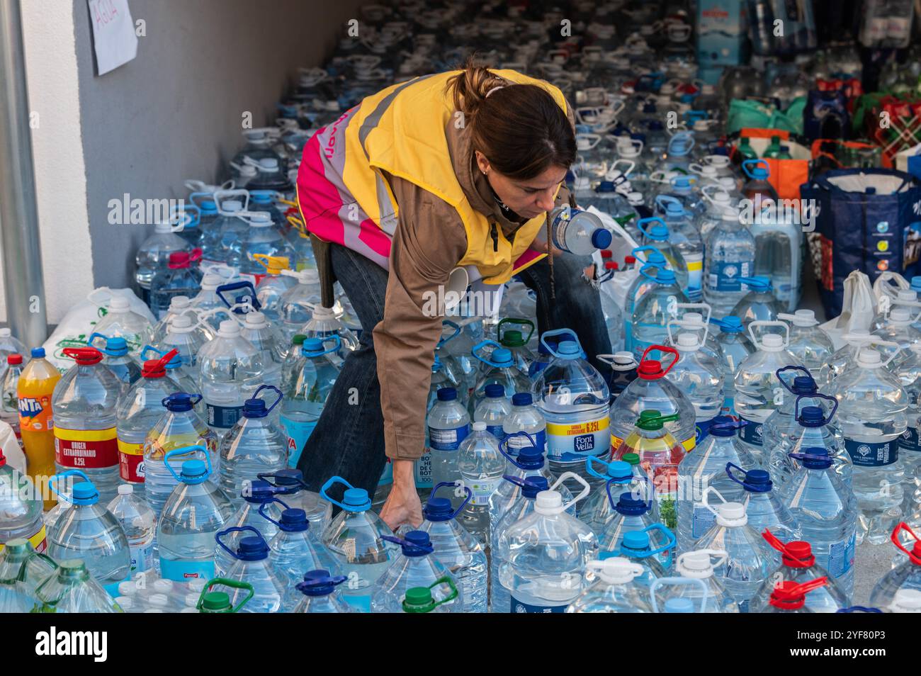 A volunteer organizing citizen donations of water at a collection point ...