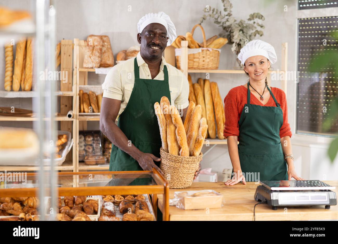 Portrait of two bakery employees - man and woman showing delicious ...