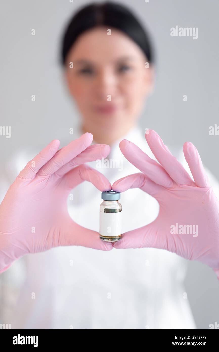 Female cosmetologist in pink gloves holding medicine bottle for ...