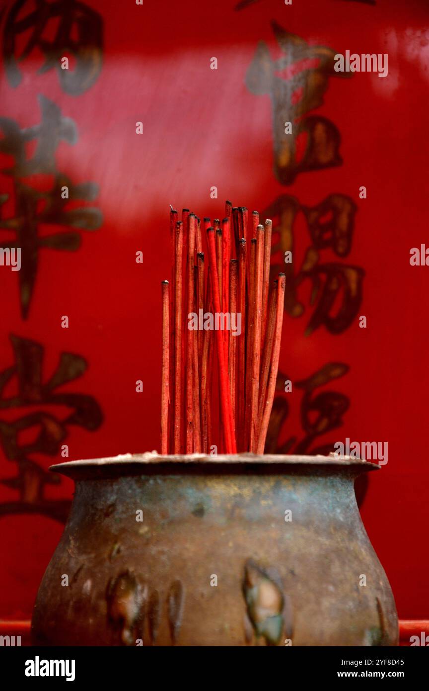 Chinese incense in a copper barrel with Chinese writing as a background ...