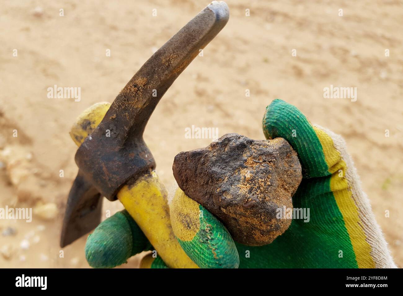 Pickaxe and iron ore sample in hand, field photo from geological hike ...
