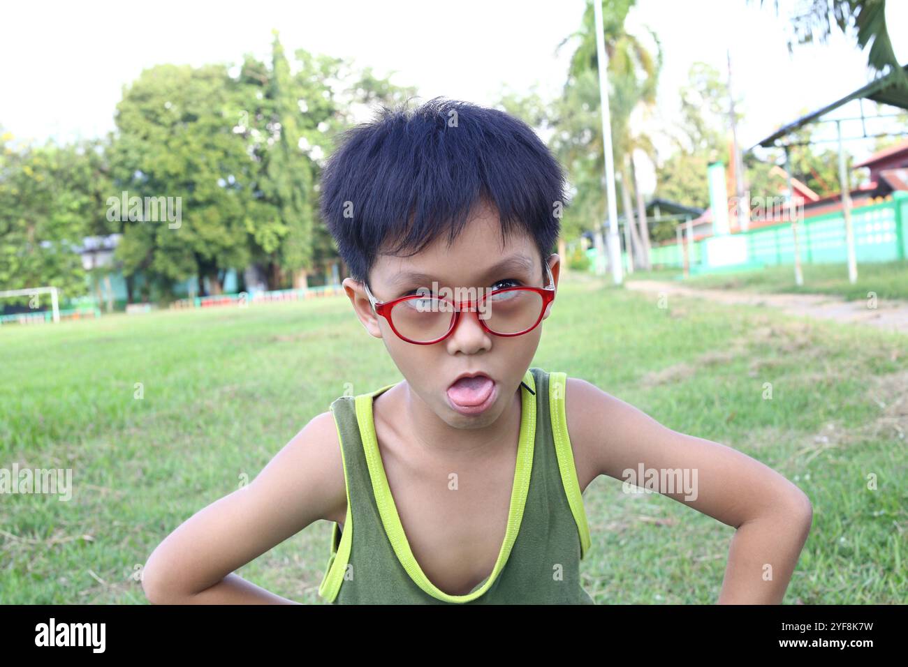 A playful boy makes a silly face outdoors, showcasing his fun-loving ...