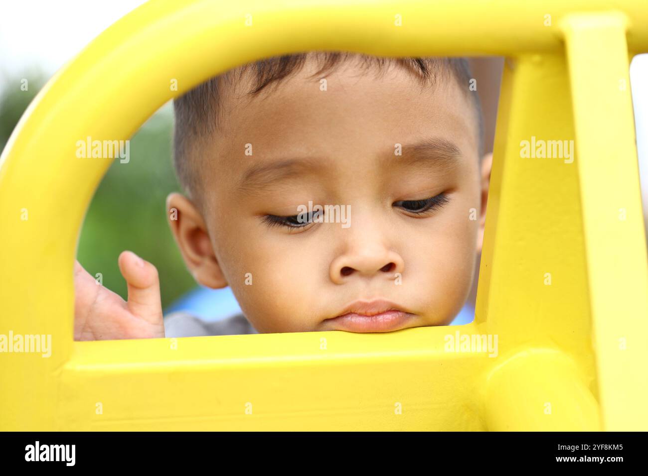 A close-up of a child exploring a vibrant yellow playground structure ...