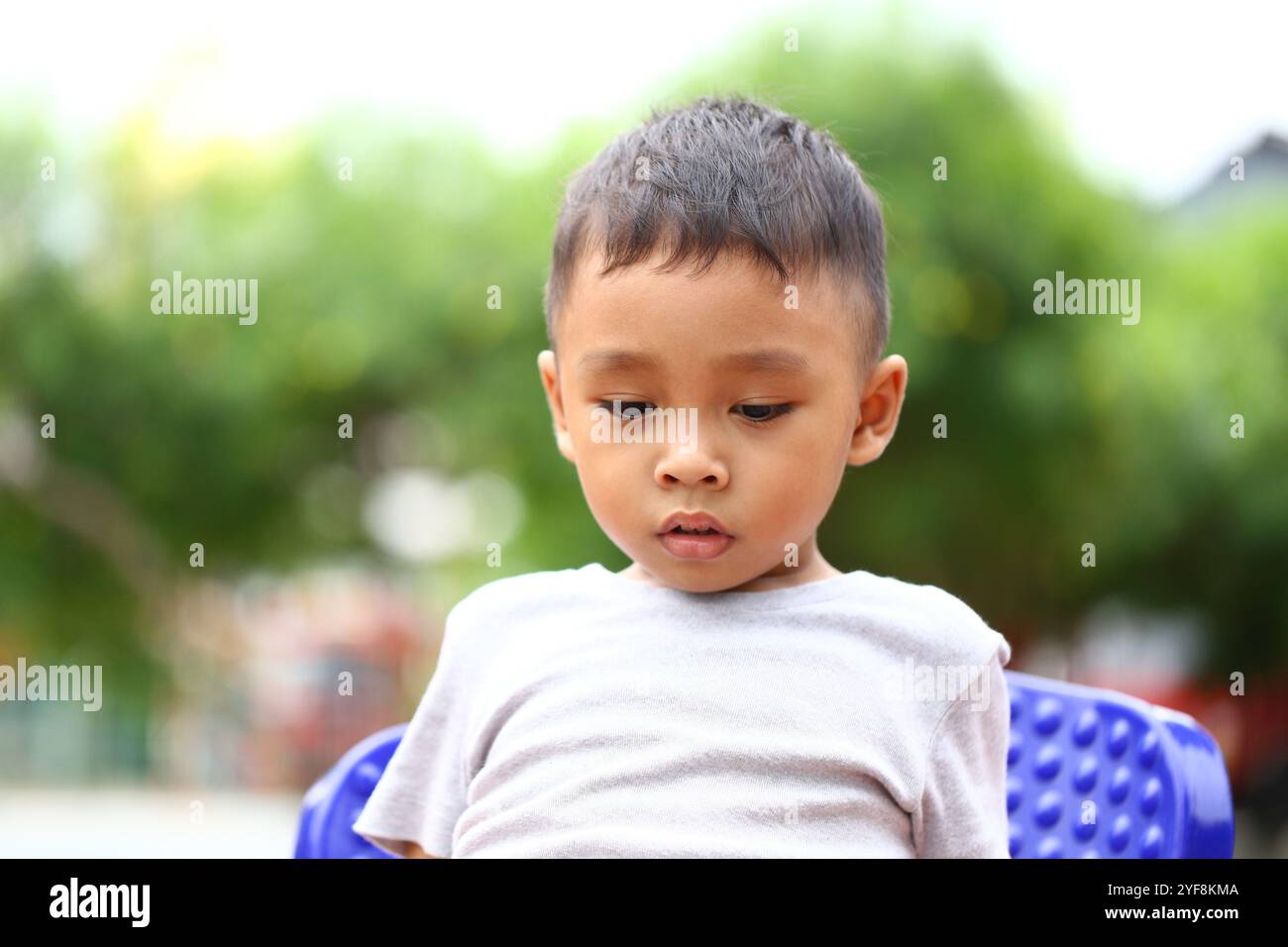 A contemplative boy sits on playground equipment, lost in thought. The ...