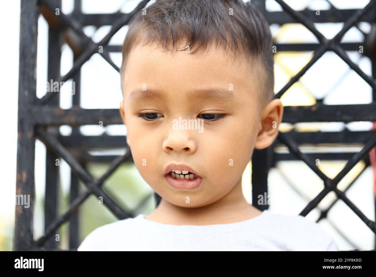 A young boy outdoors shows a thoughtful expression, capturing the ...