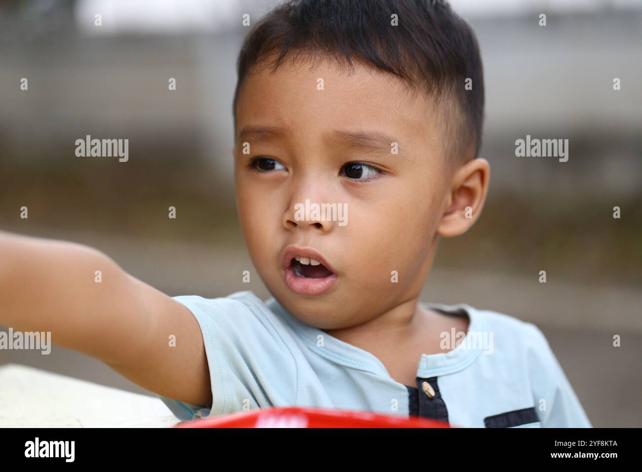 A young boy is captured mid-gesture, expressing curiosity and joy ...