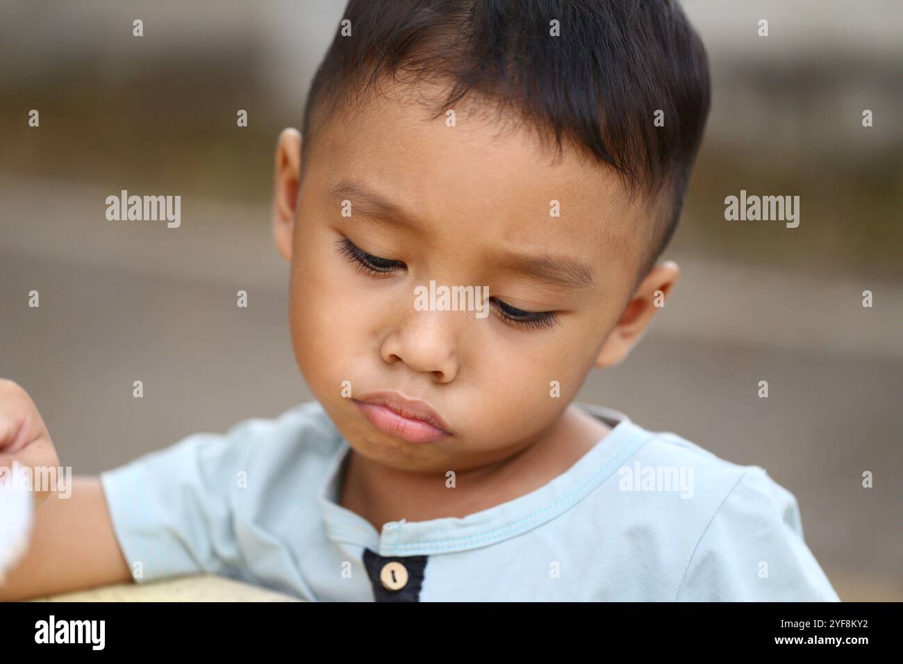 This close-up portrait captures a pensive child deep in thought ...