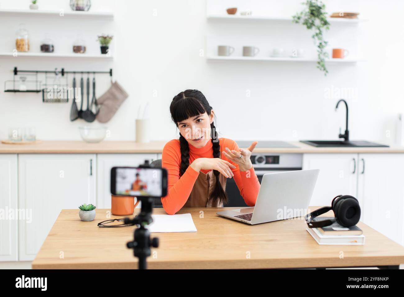 Young woman vlogging in modern kitchen with camera setup Stock Photo ...