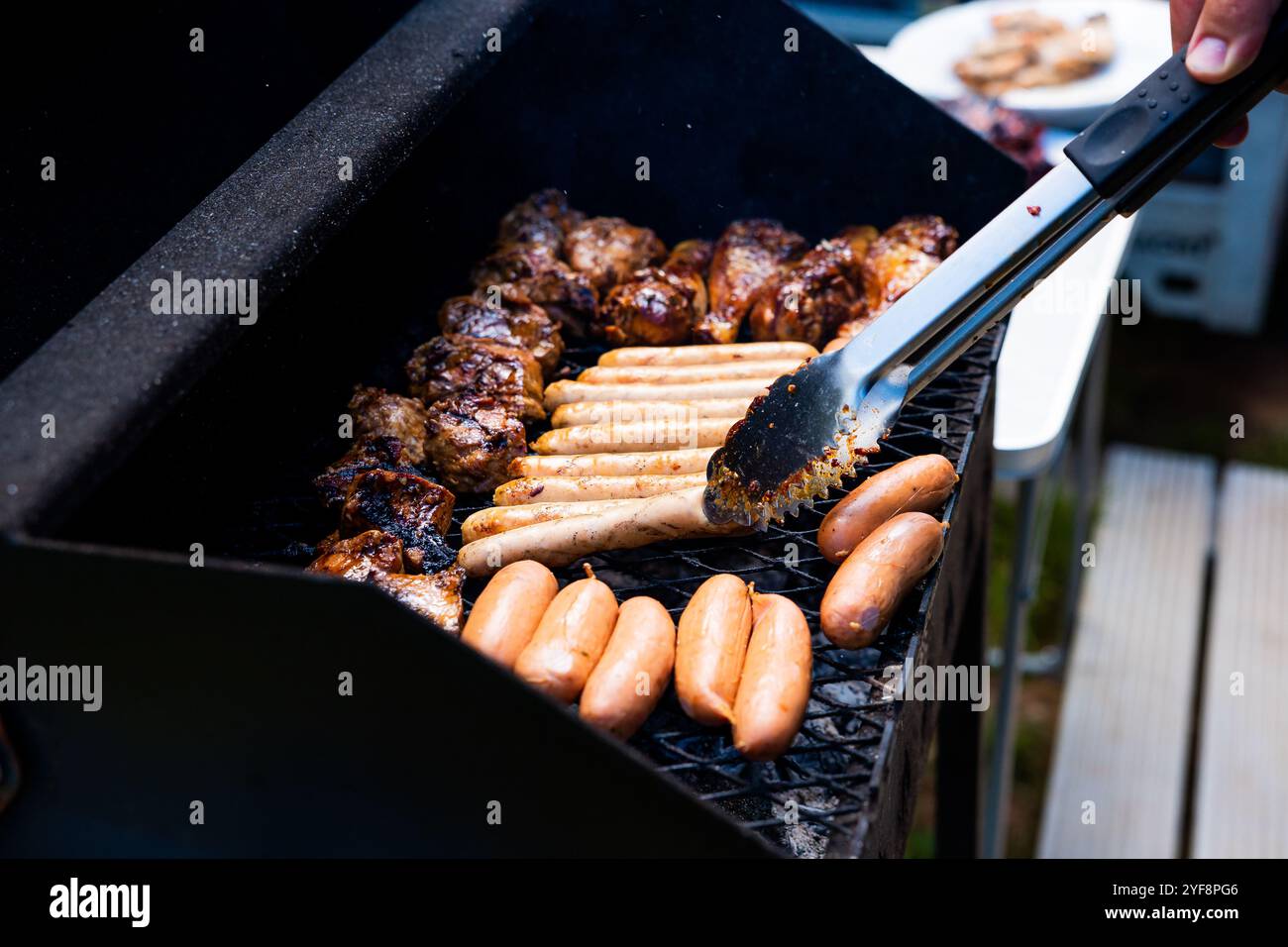 A man grills meat and sausages in the yard of a house Stock Photo - Alamy