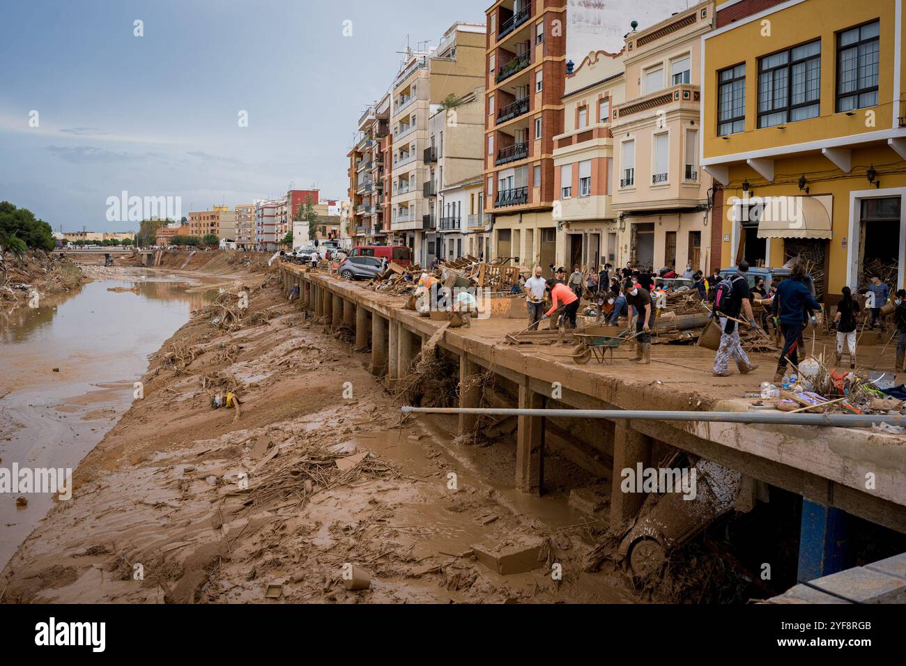 Locals and volunteers are seen manually cleaning up the streets filled ...