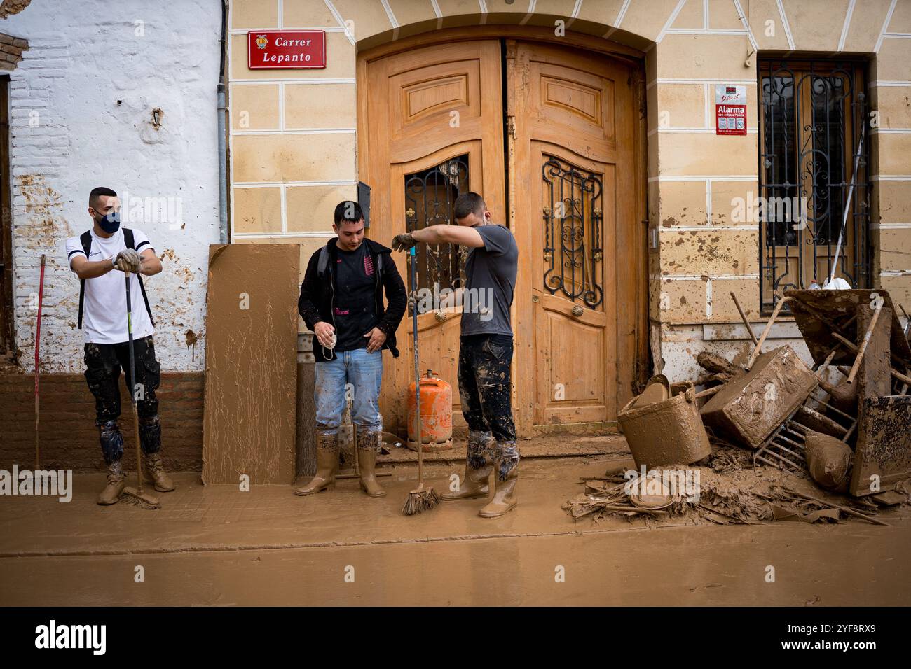 Locals and volunteers are seen manually cleaning up the streets filled ...