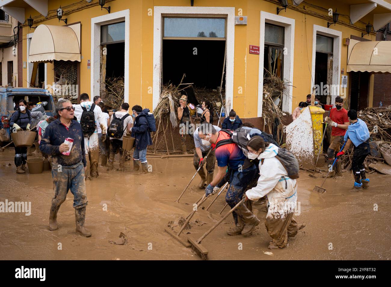 Locals and volunteers are seen manually cleaning up the streets filled ...