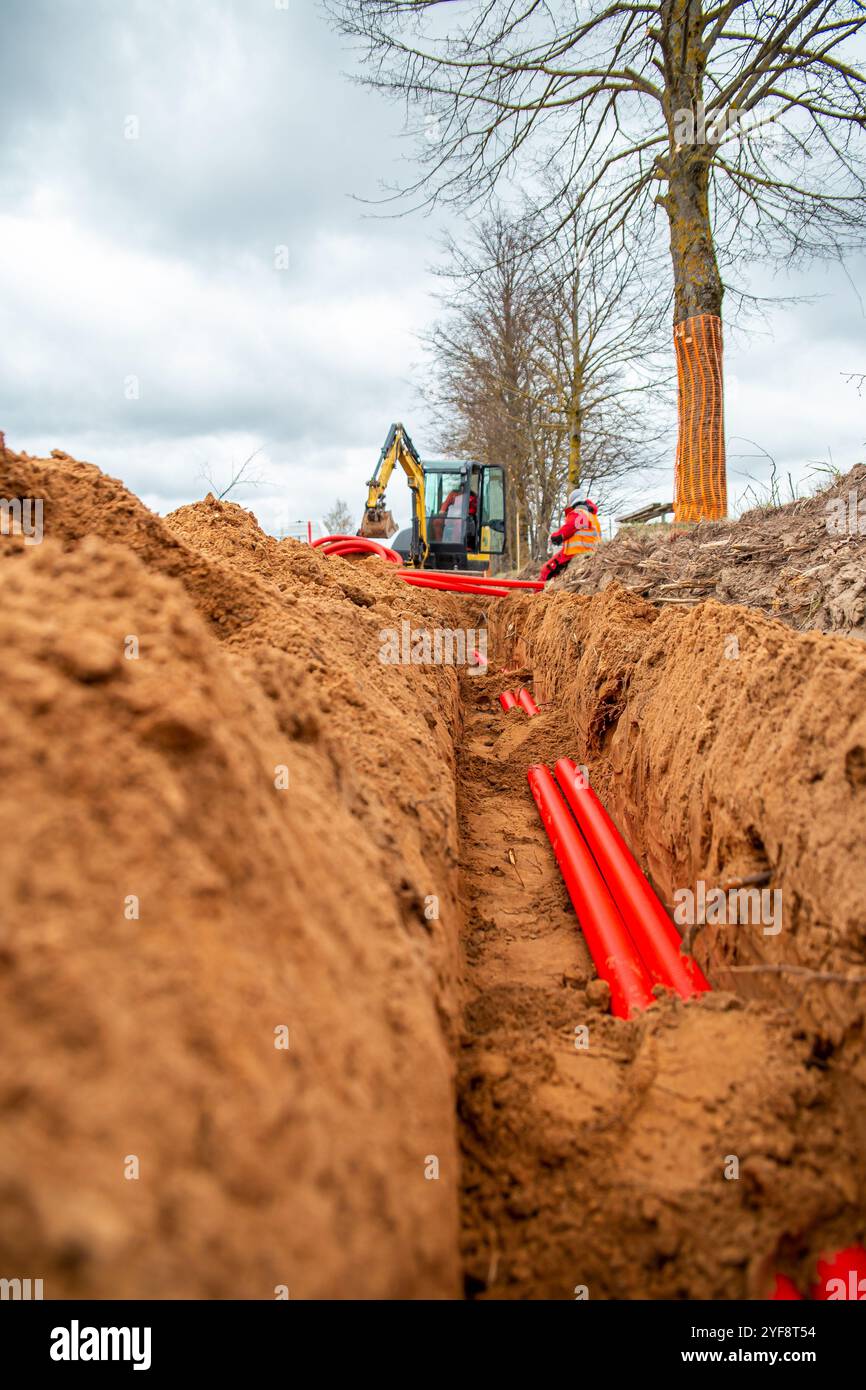 Network cables in red corrugated pipe are buried underground on the ...