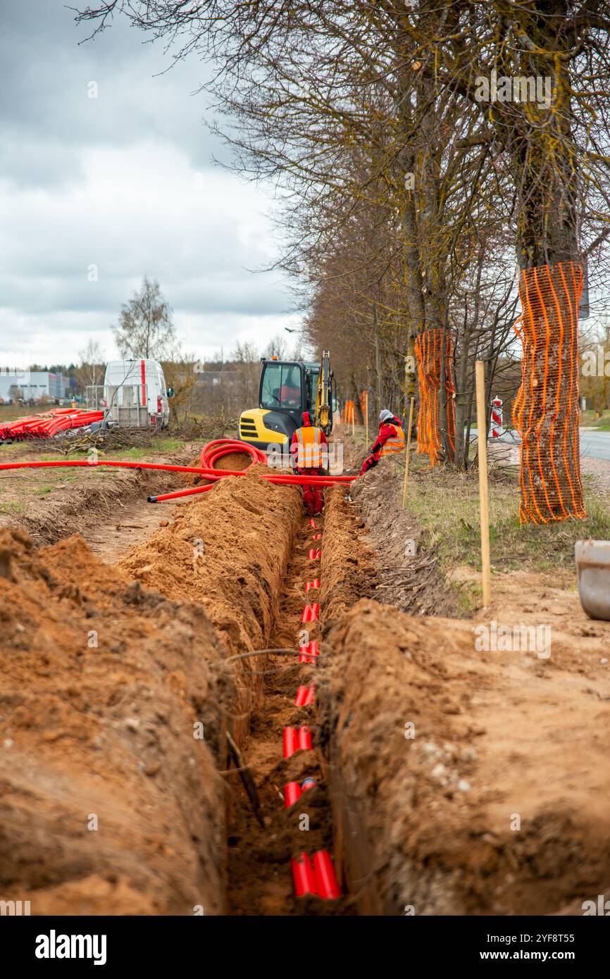 Network cables in red corrugated pipe are buried underground on the ...