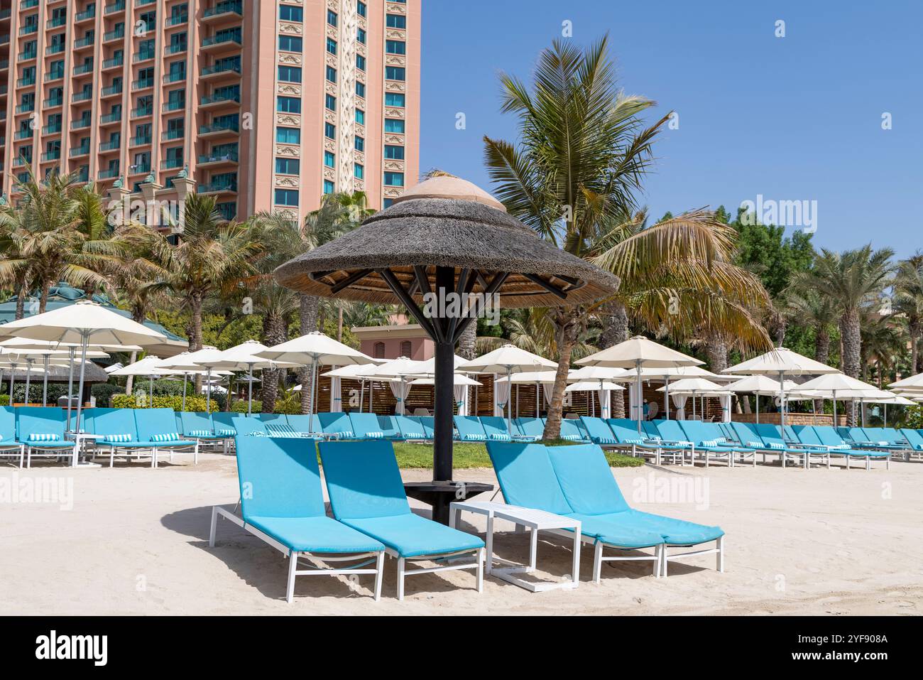 Sunloungers on the sandy beach beneath a thatched shade umbrella at the ...