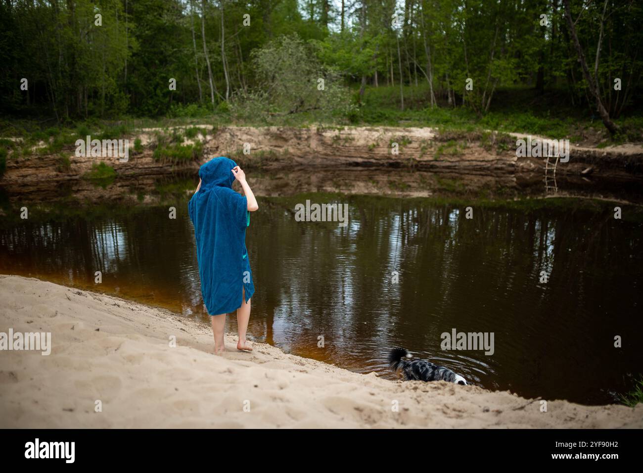 Woman in Blue Poncho poses by Riverside with Her Dog Stock Photo - Alamy