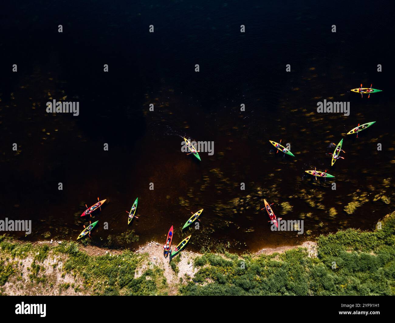 Group of colorful kayaks in a row on a dark water river with ...