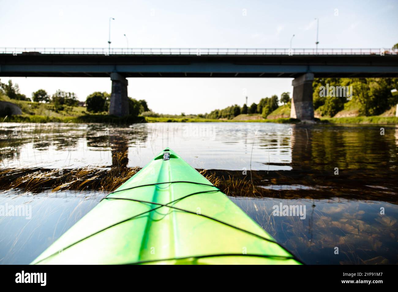 First-person view from a kayak approaching a bridge on a peaceful river ...