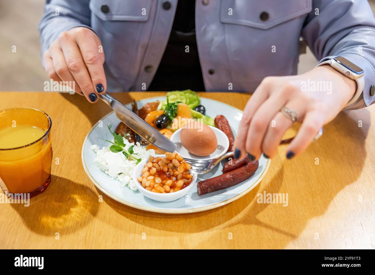 Woman eating Full English Breakfast with Beans, Sausages, Boiled Eggs ...