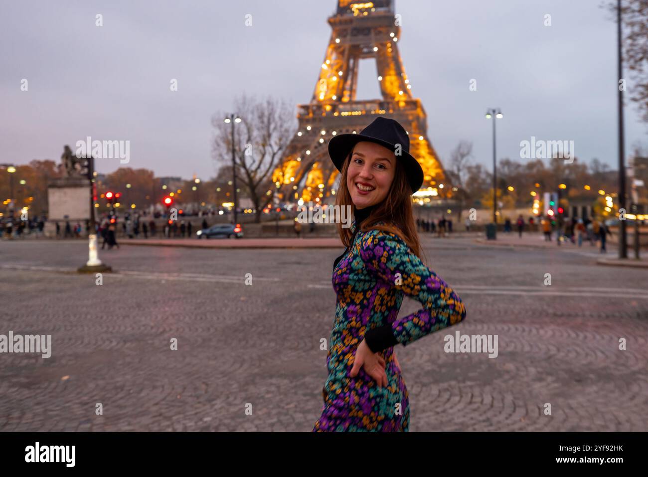 Fashionable woman in floral dress and hat posing with the illuminated ...