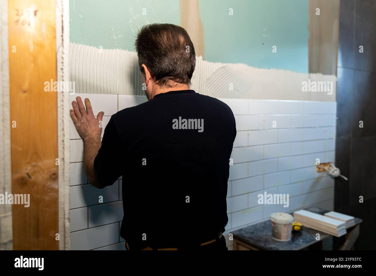Professional tiler applying ceramic tiles to the wall in a modern ...