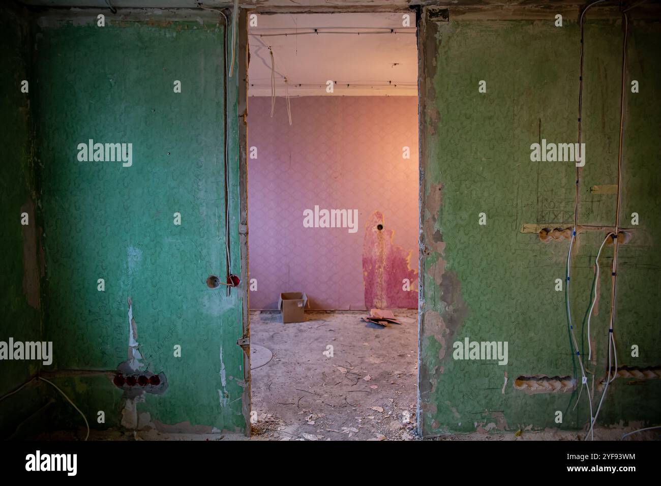 Abandoned building interior in disrepair with debris, exposed pipes, and missing doors awaiting ...