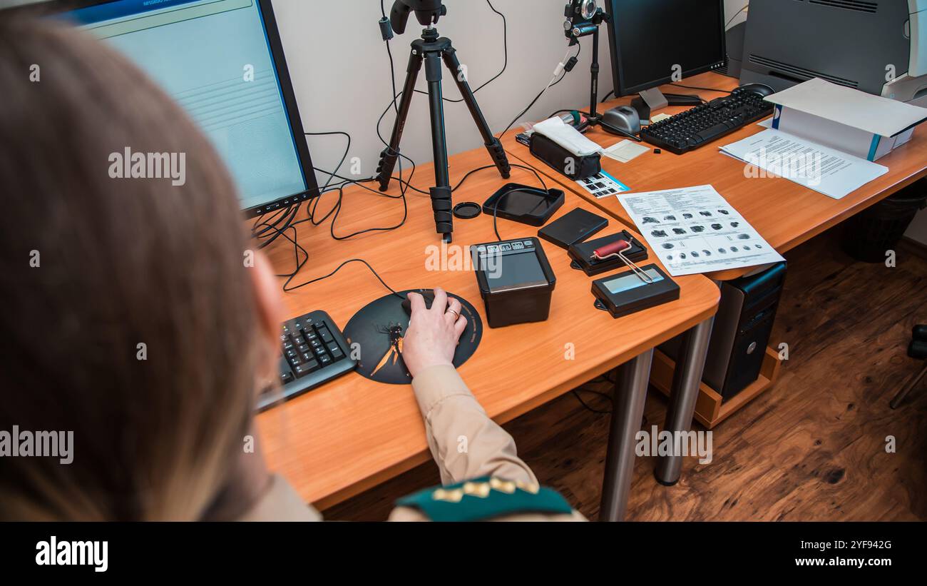 Forensic expert taking fingerprints for identification with ink pad and ...
