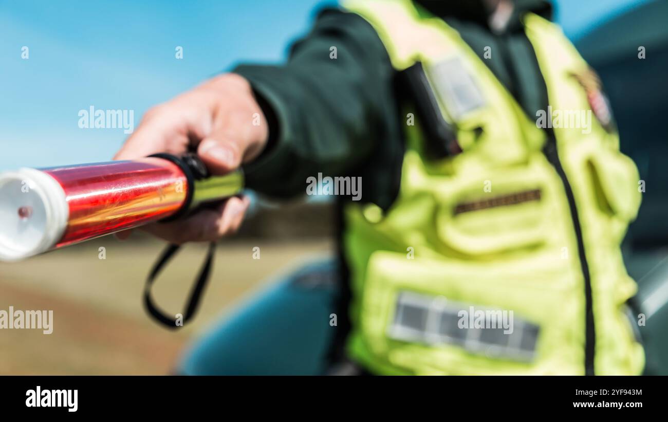 Traffic officer in high-visibility vest holding a baton for road ...