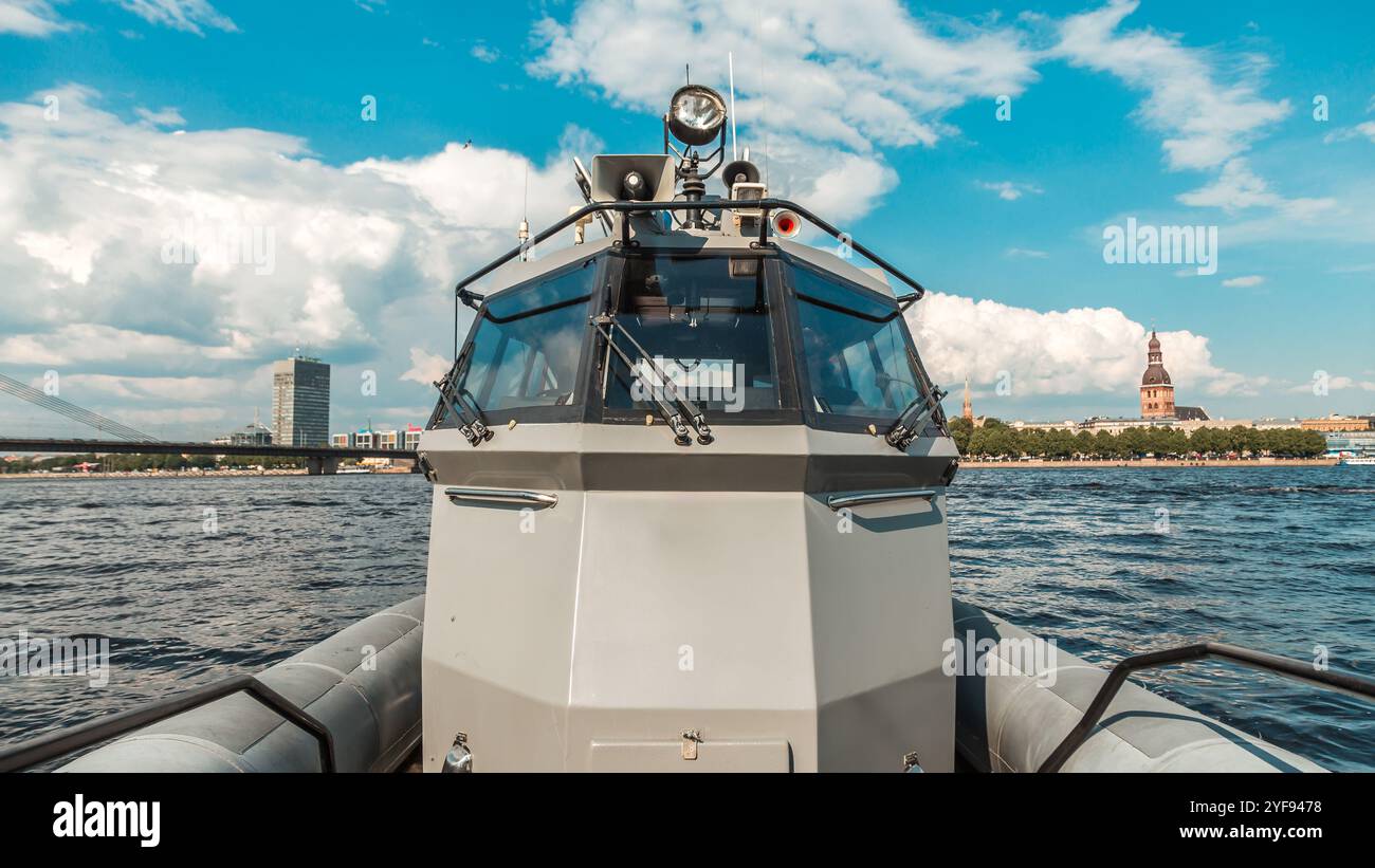 Modern military patrol boat cruising on the river with a city in ...