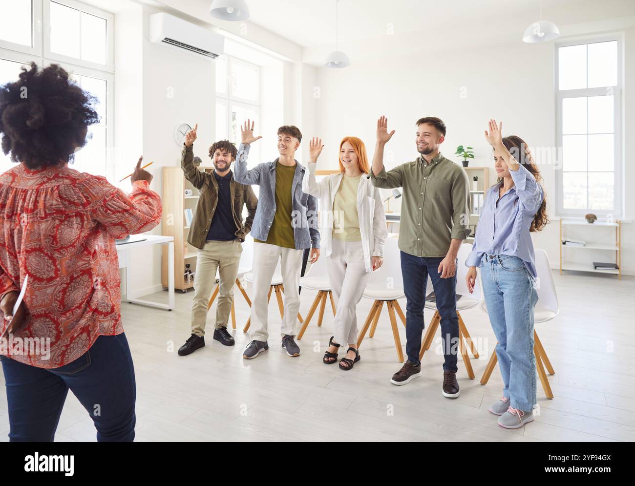 Young cheerful company employees raising hands to vote at the ...