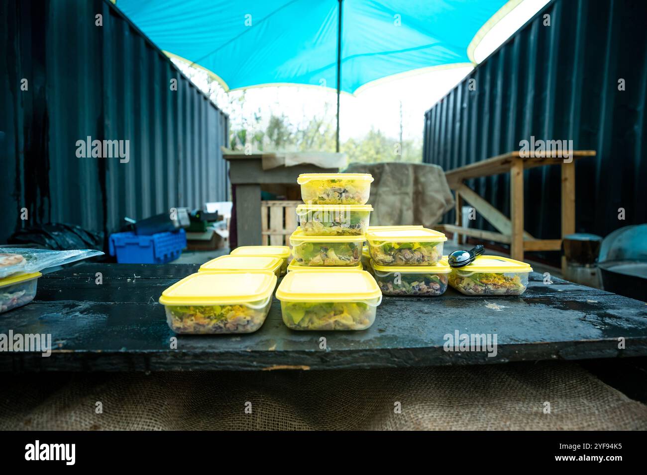 prepared meal containers lined up on a rustic workbench at an outdoor ...