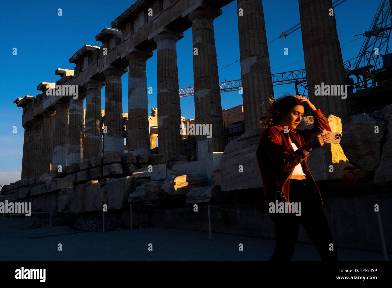 Tourist in front of the Parthenon temple under renovation construction with crane and ...