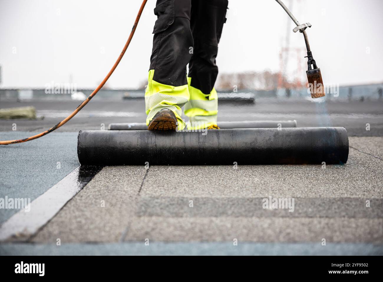 professional roofer applying tar with blowtorch on new roofing felt for ...