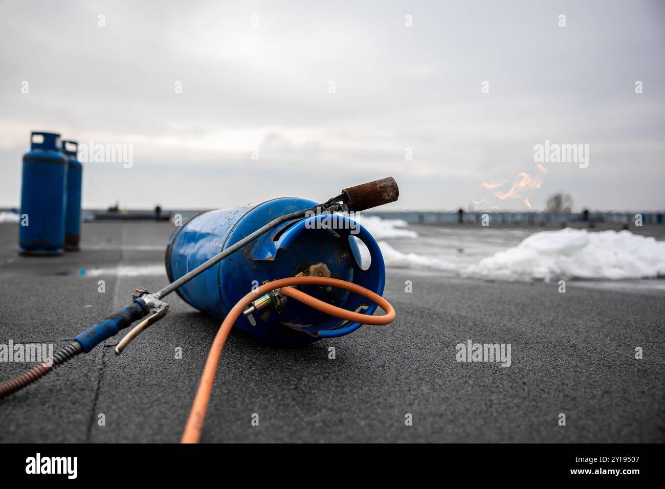 gas torch tool lying on new roofing surface with propane tank and hose ...