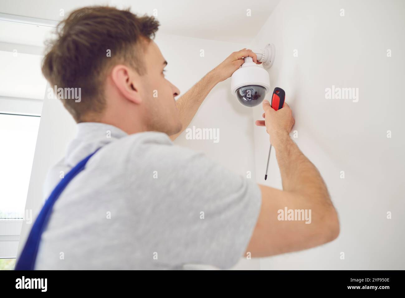 Technician man installing surveillance CCTV camera with screwdriver on ...