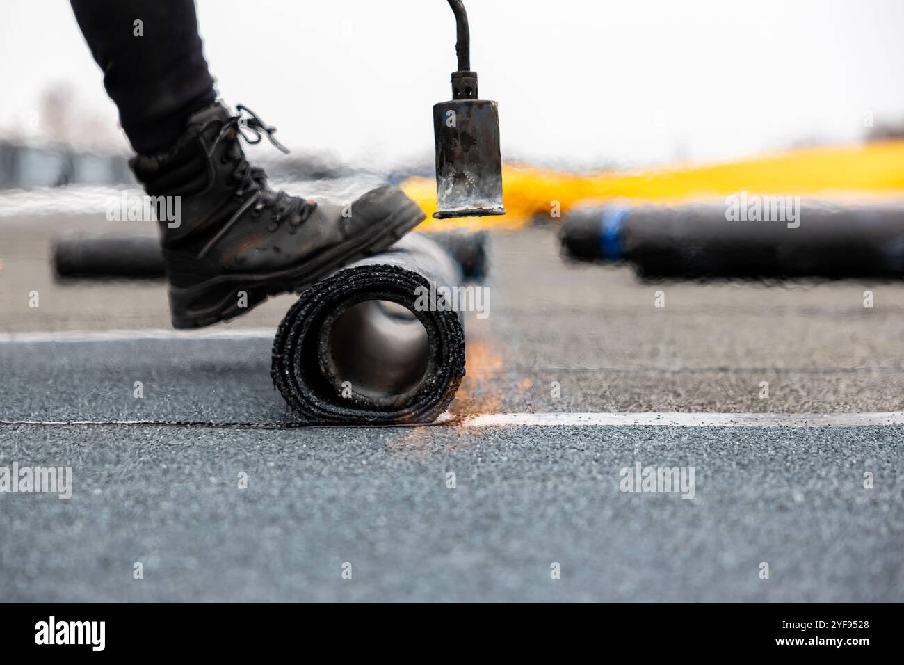 professional roofer at work securing rolled tar paper with a blowtorch ...