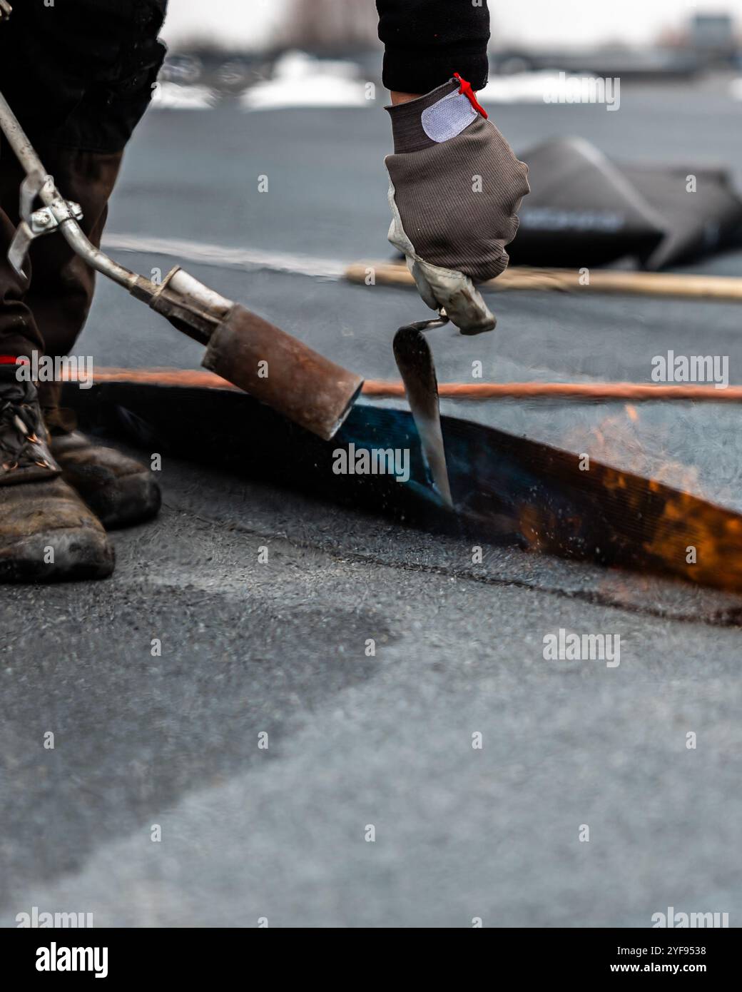 professional roofer applying bitumen roll on flat roof with a gas ...