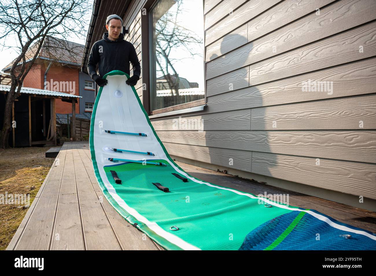 Man folding an inflatable stand-up paddleboard (SUP) on a wooden deck ...