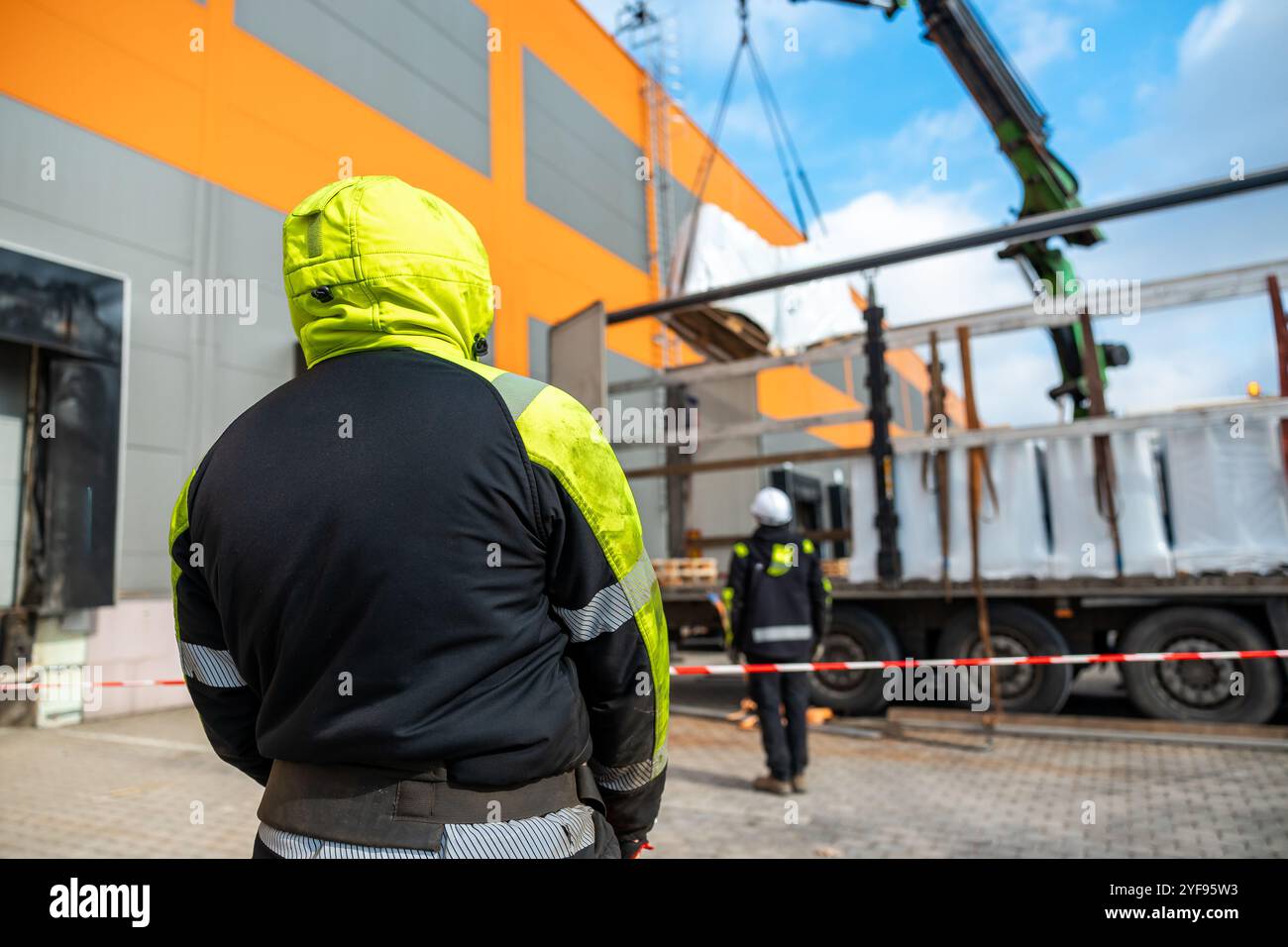 Construction Site Supervisor Overseeing Cargo Unloading with Crane at ...