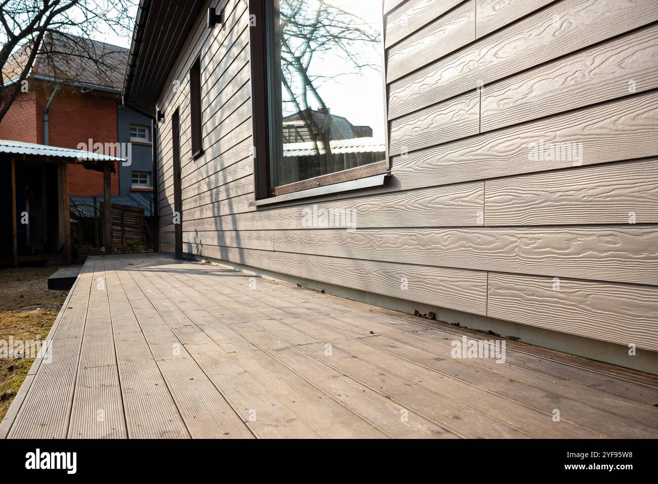 Spacious Wooden Deck Leading to a Modern House with Textured Siding ...