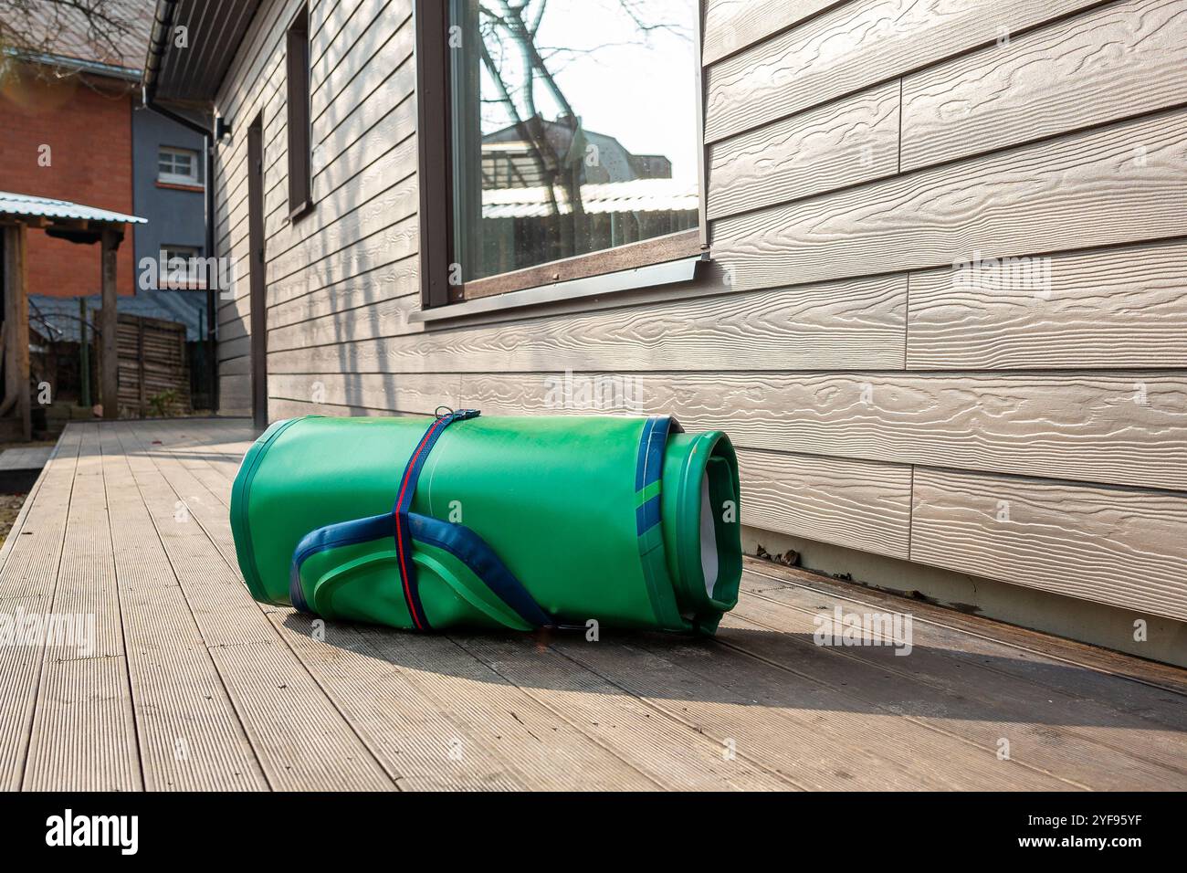 Green Inflatable Stand-Up Paddle Board Rolled Up Next to Wooden House ...