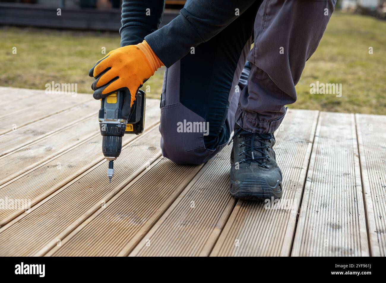 Deck or terrace construction, builder hand with electric screwdriver ...