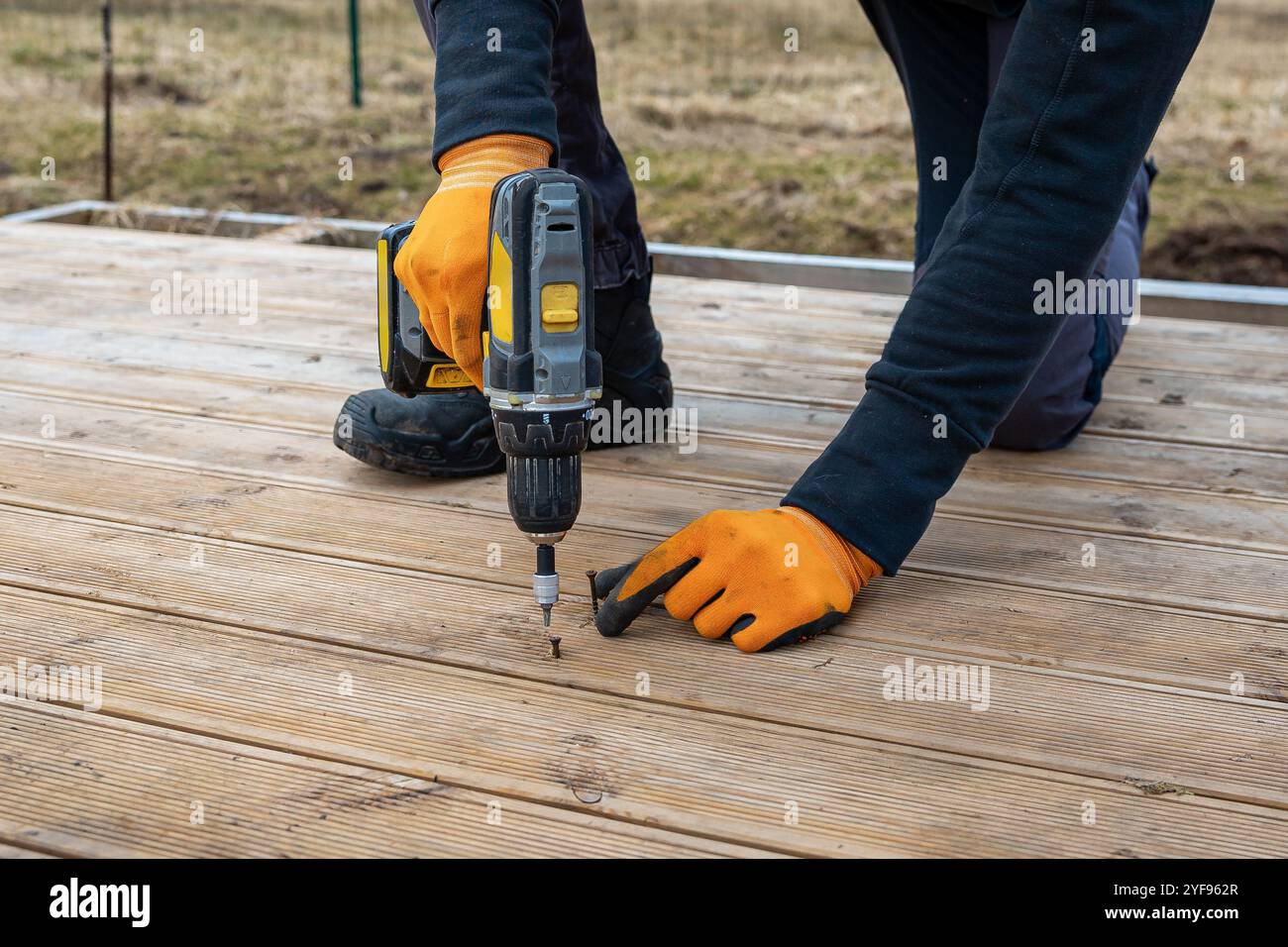 Deck or terrace construction, builder hand with electric screwdriver ...