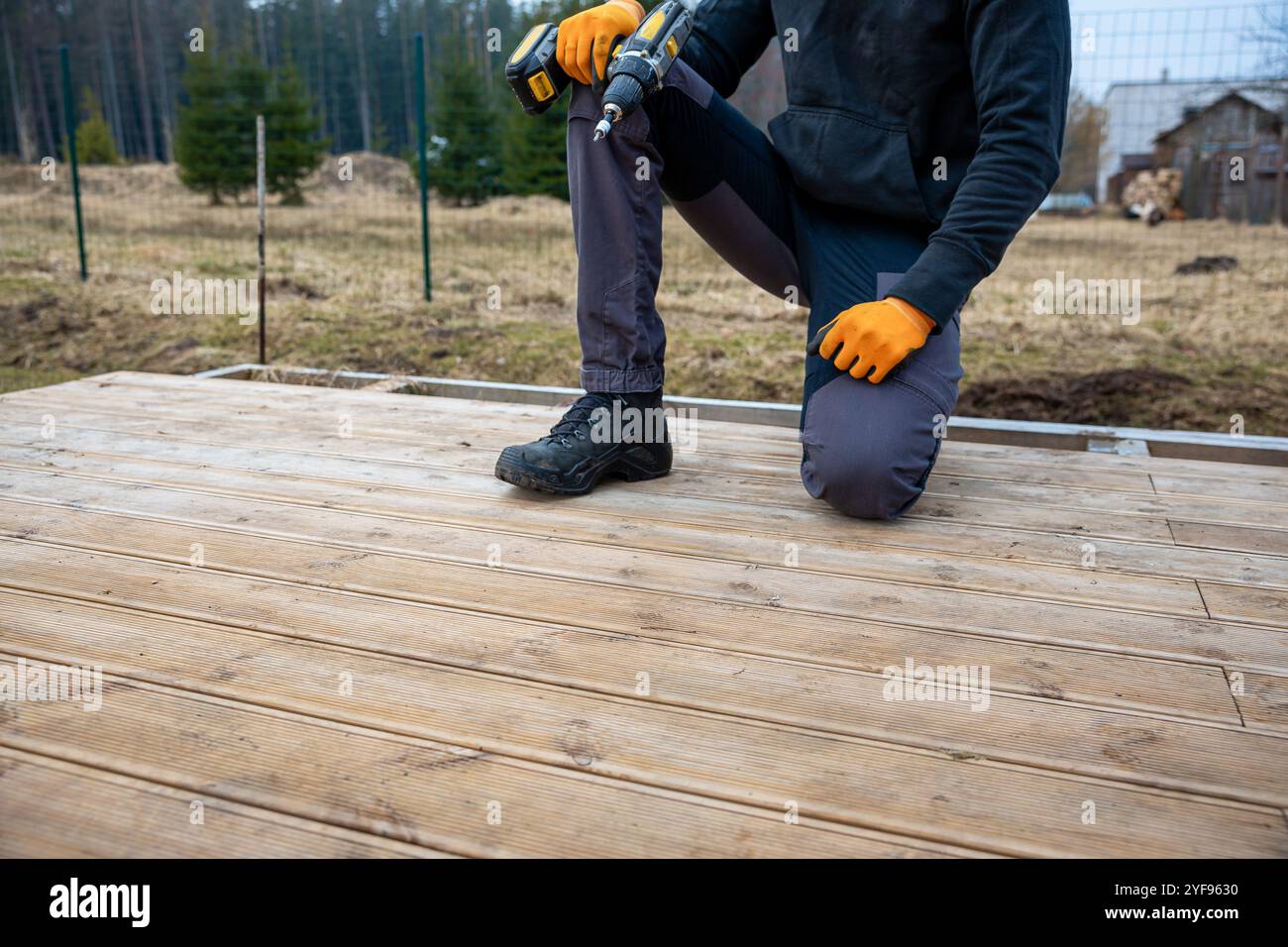 Deck or terrace construction, builder hand with electric screwdriver ...