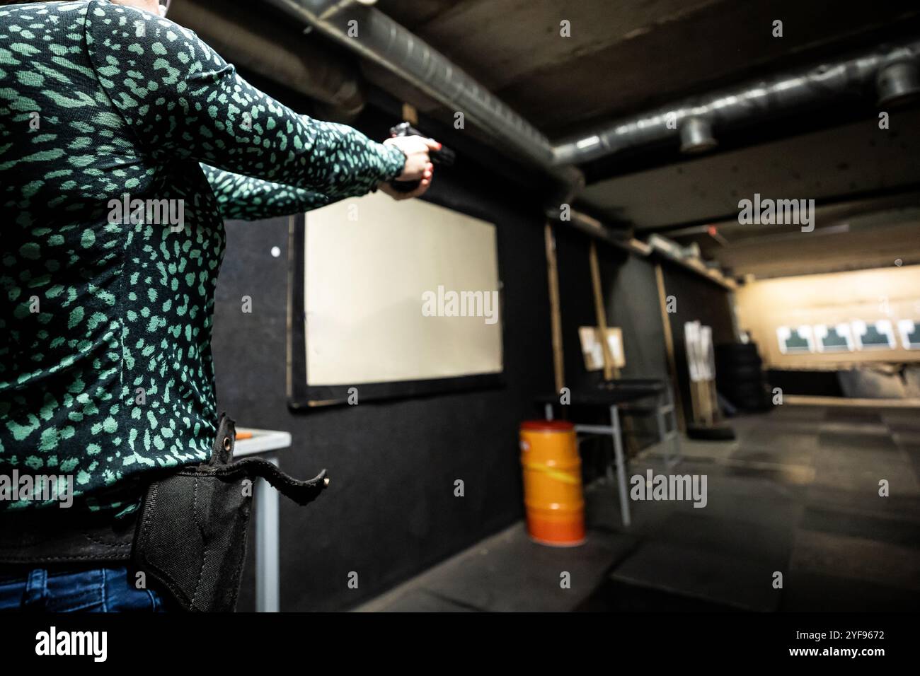 focused shooter practicing aim at indoor gun range with visible targets ...