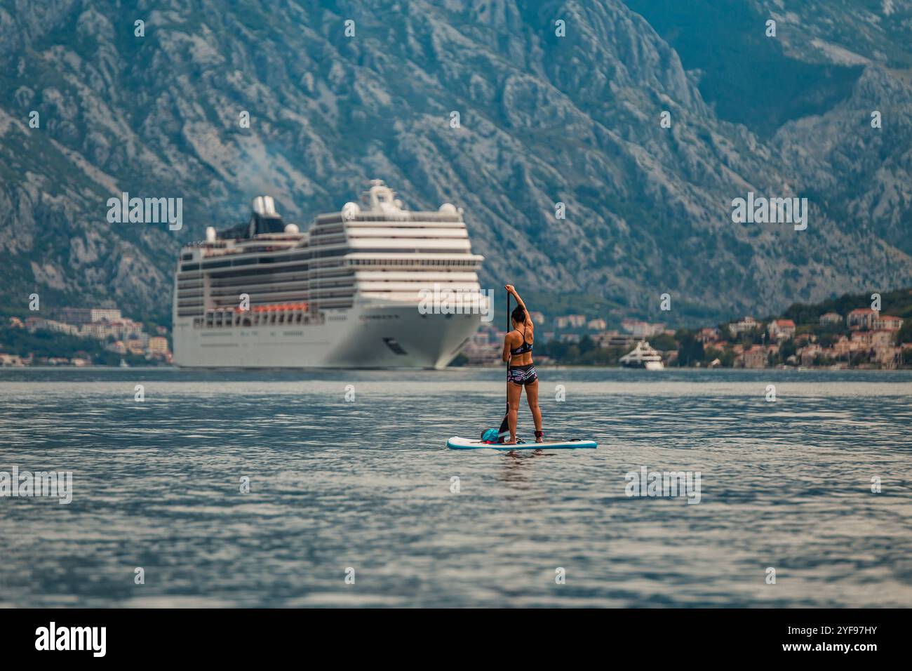 solo paddle boarder in front of a towering cruise ship with a stunning ...