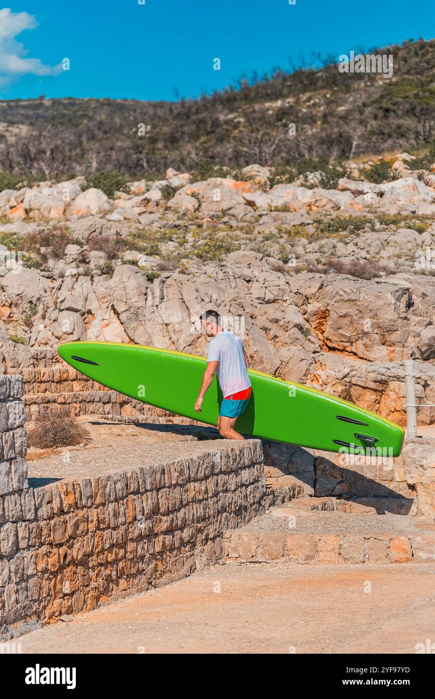 Man carrying paddleboard into sea hi-res stock photography and images ...