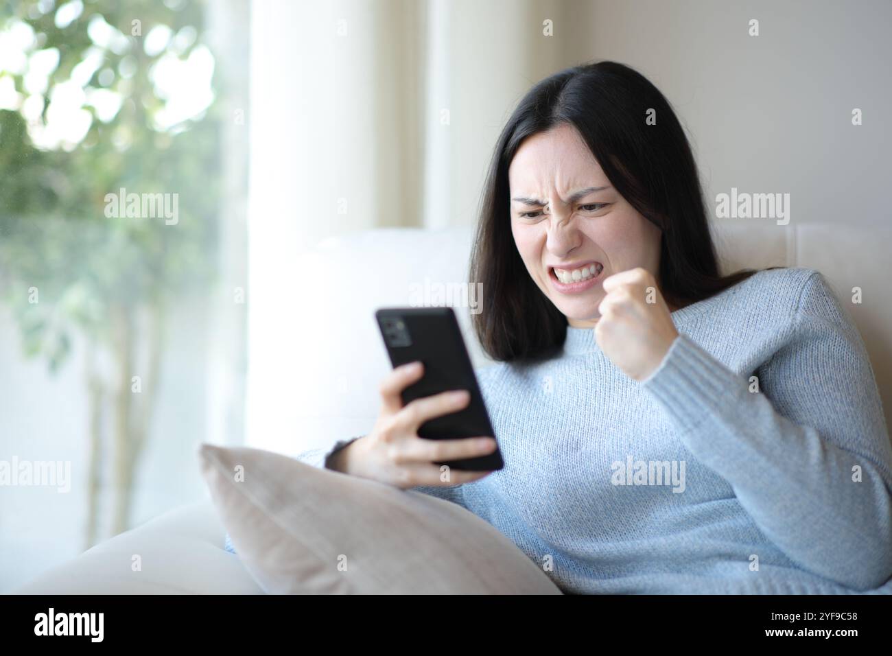 Angry asian woman checking phone annoying content at home Stock Photo - Alamy